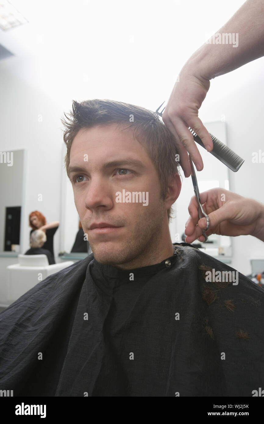 Handsome young man getting haircut in hair salon Stock Photo - Alamy