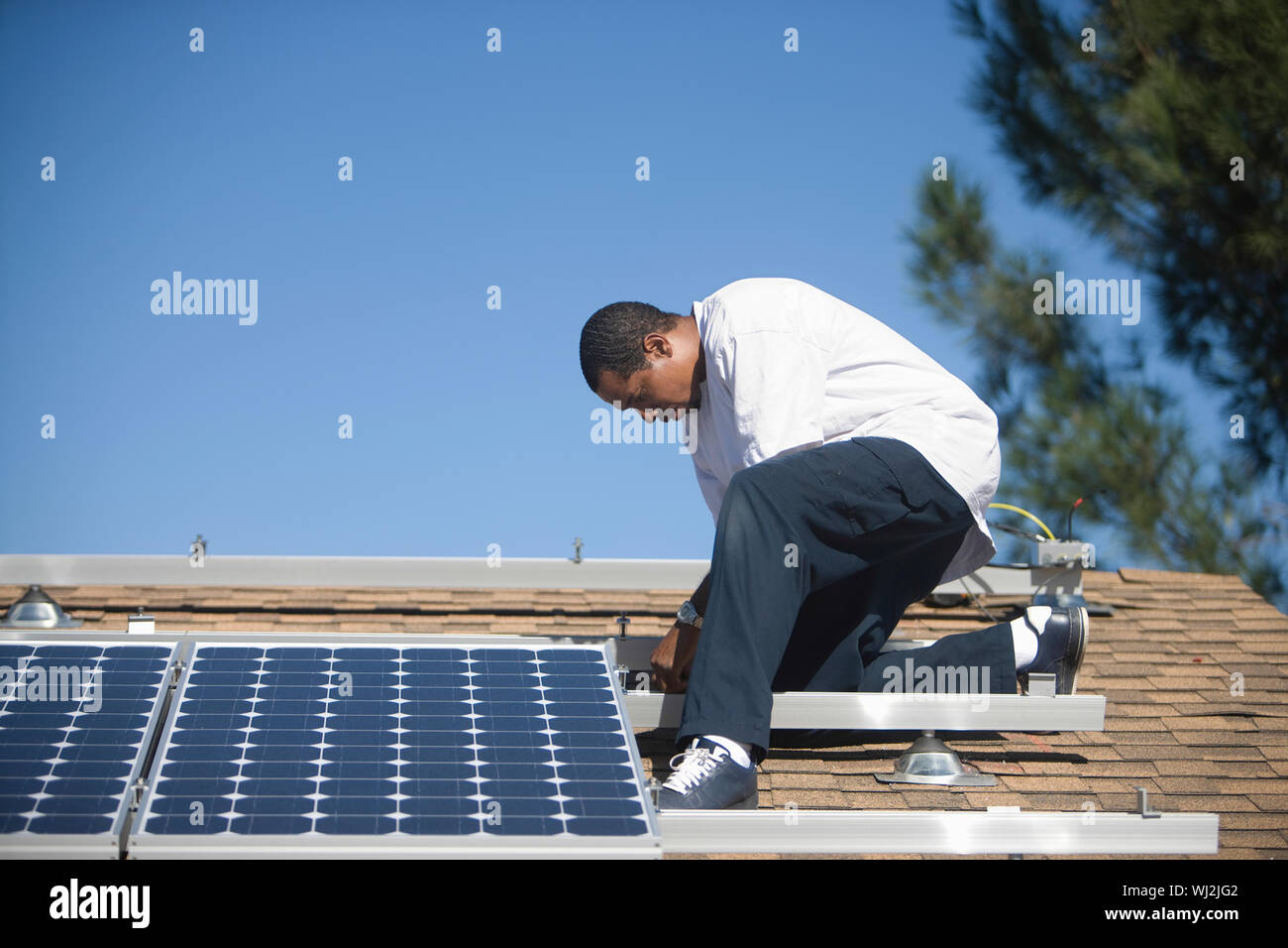 Full length side view of an African American man fixing solar panel on ...