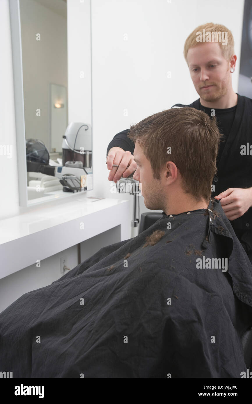 Young man getting an haircut from hairdresser in hair salon Stock Photo ...