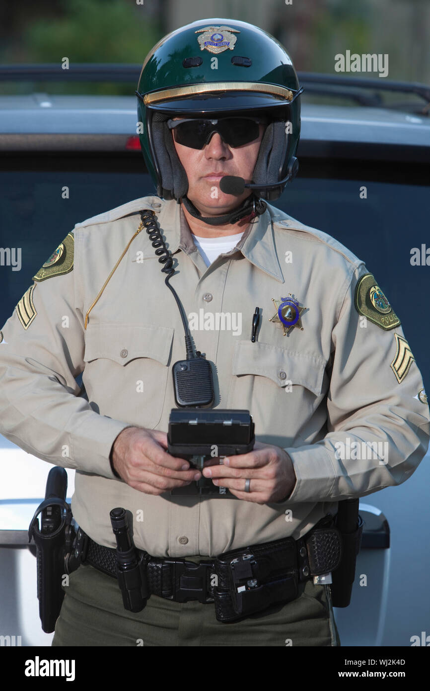 Portrait of middle aged traffic cop with clipboard standing against car ...