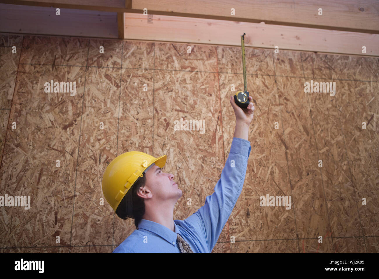 Caucasian male architect inspecting framework with measure tape at ...