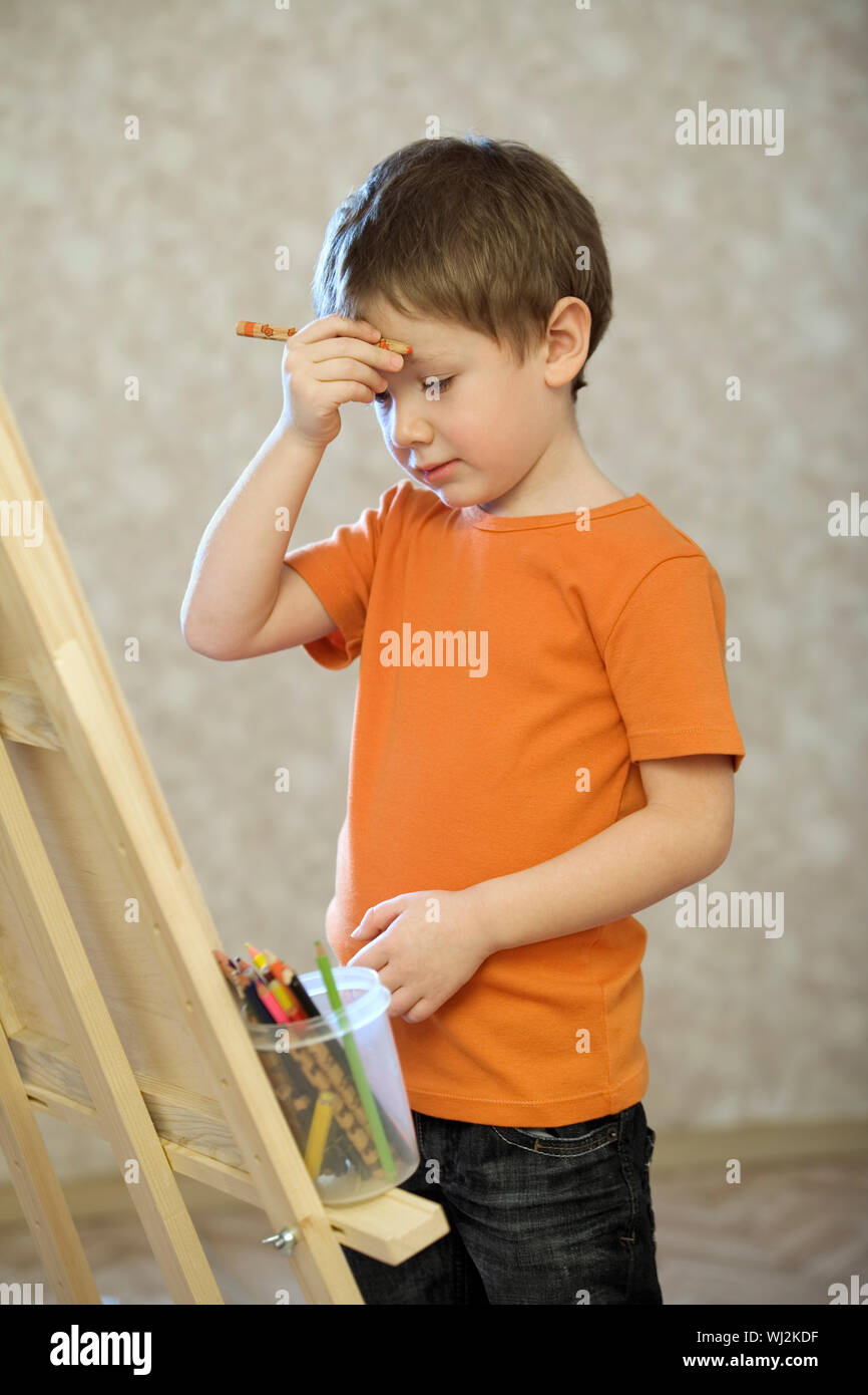 Confused boy with hand on forehead standing in front of easel Stock ...