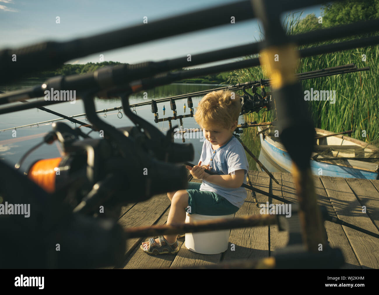 Boy fishing from dock on lake Stock Photo - Alamy