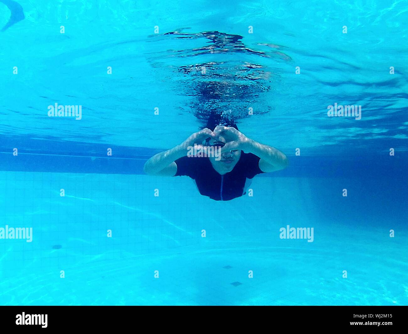 Woman Making Heart Shape With Hands While Swimming In Pool Stock Photo ...