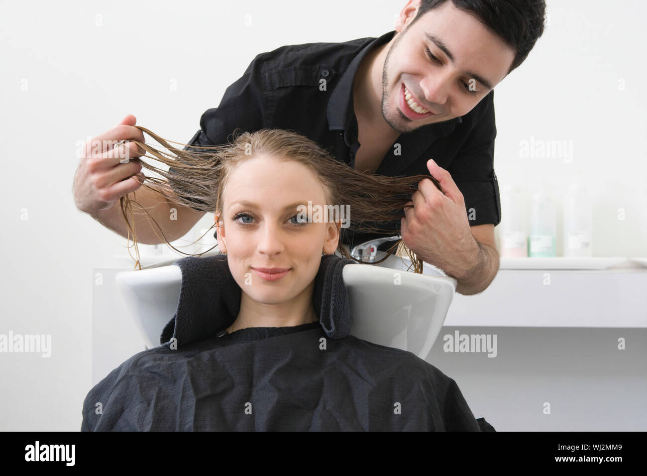 Portrait of beautiful woman smiling with hairstylist examining her hair ...