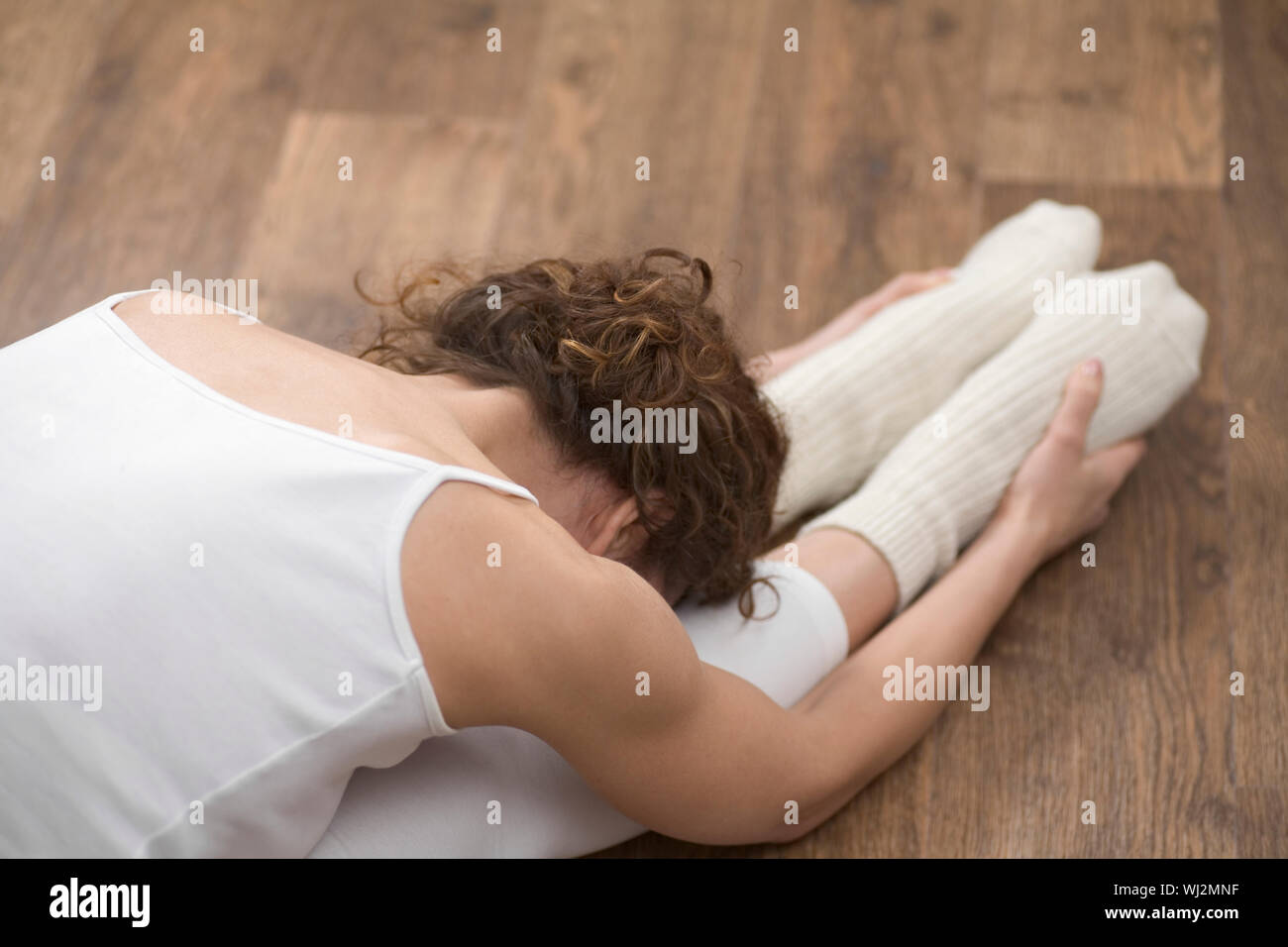 High angle view of woman doing stretching exercise on hardwood floor at ...