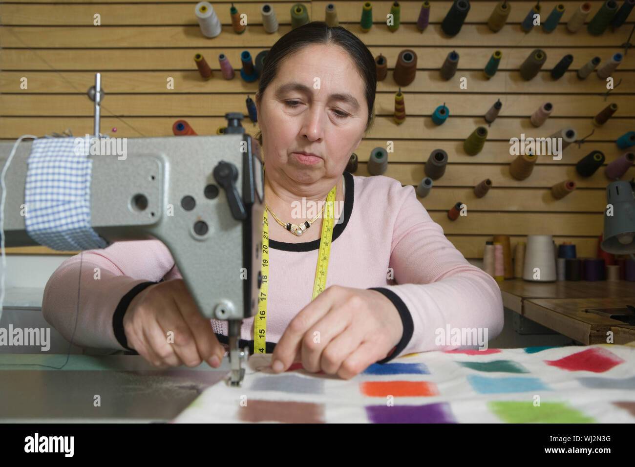 Middle aged woman using a sewing machine in laundry Stock Photo - Alamy