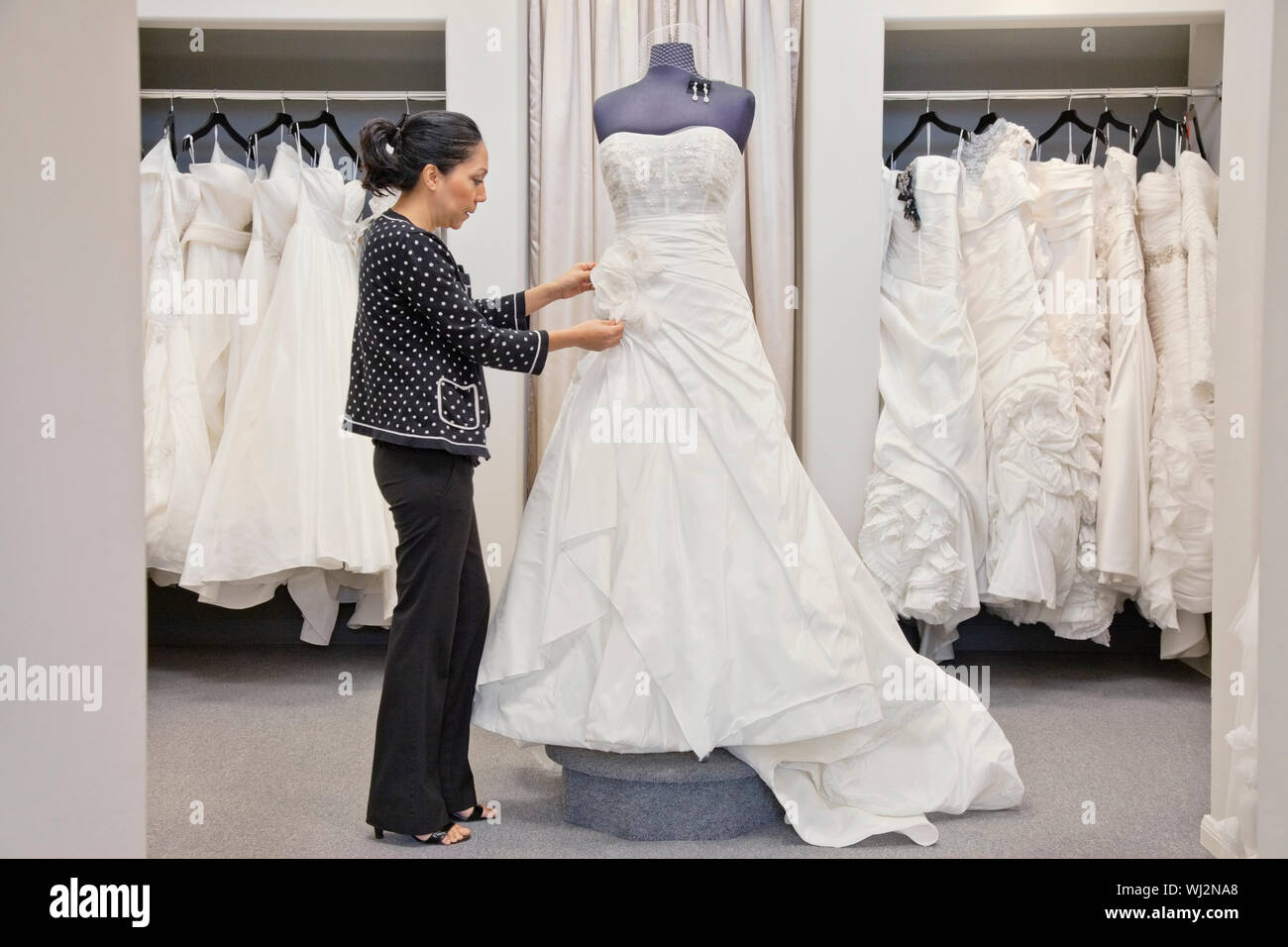 Side view of a mature employee adjusting elegant wedding dress in ...