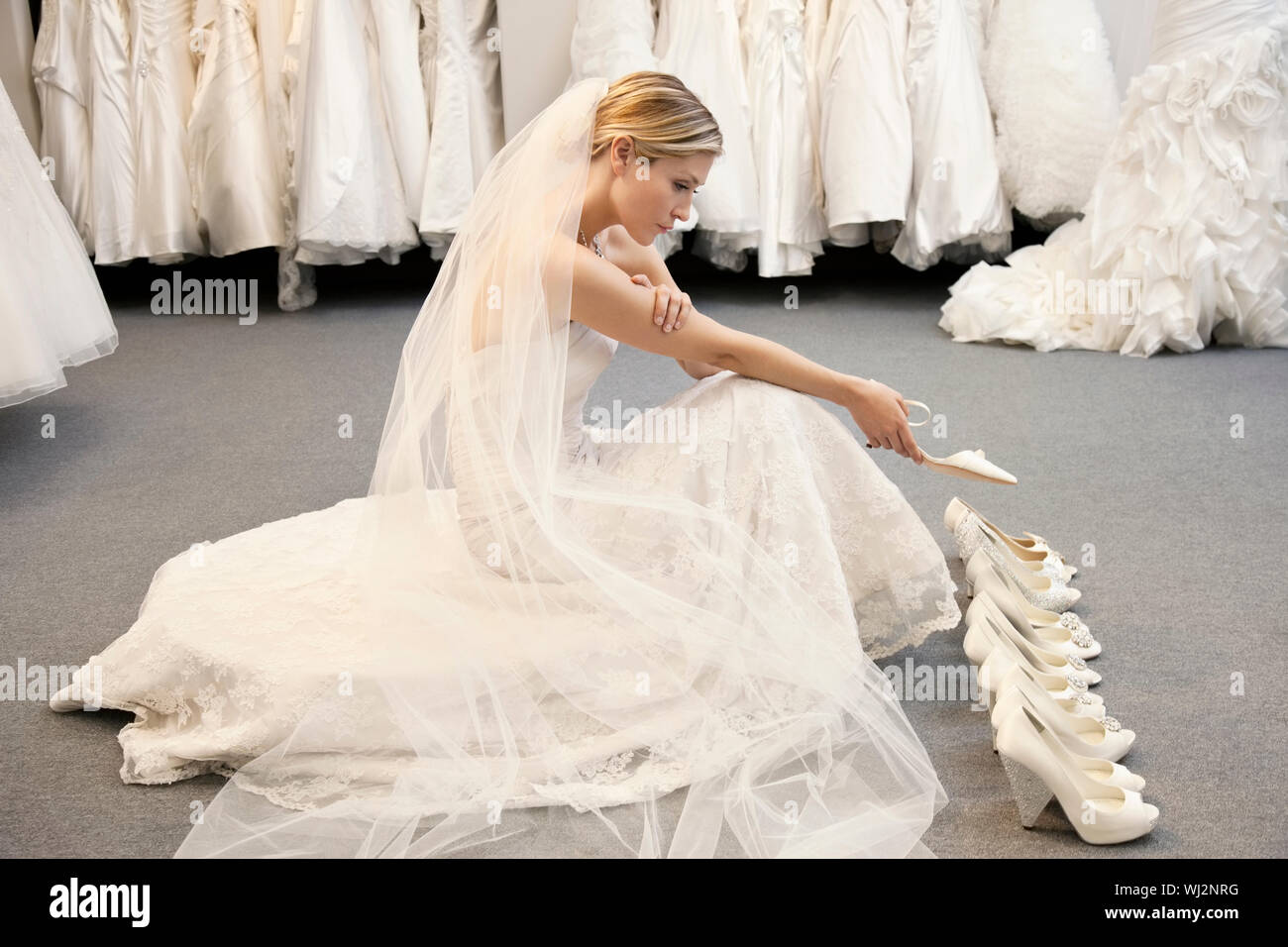 Side view of young woman in wedding dress confused while selecting ...