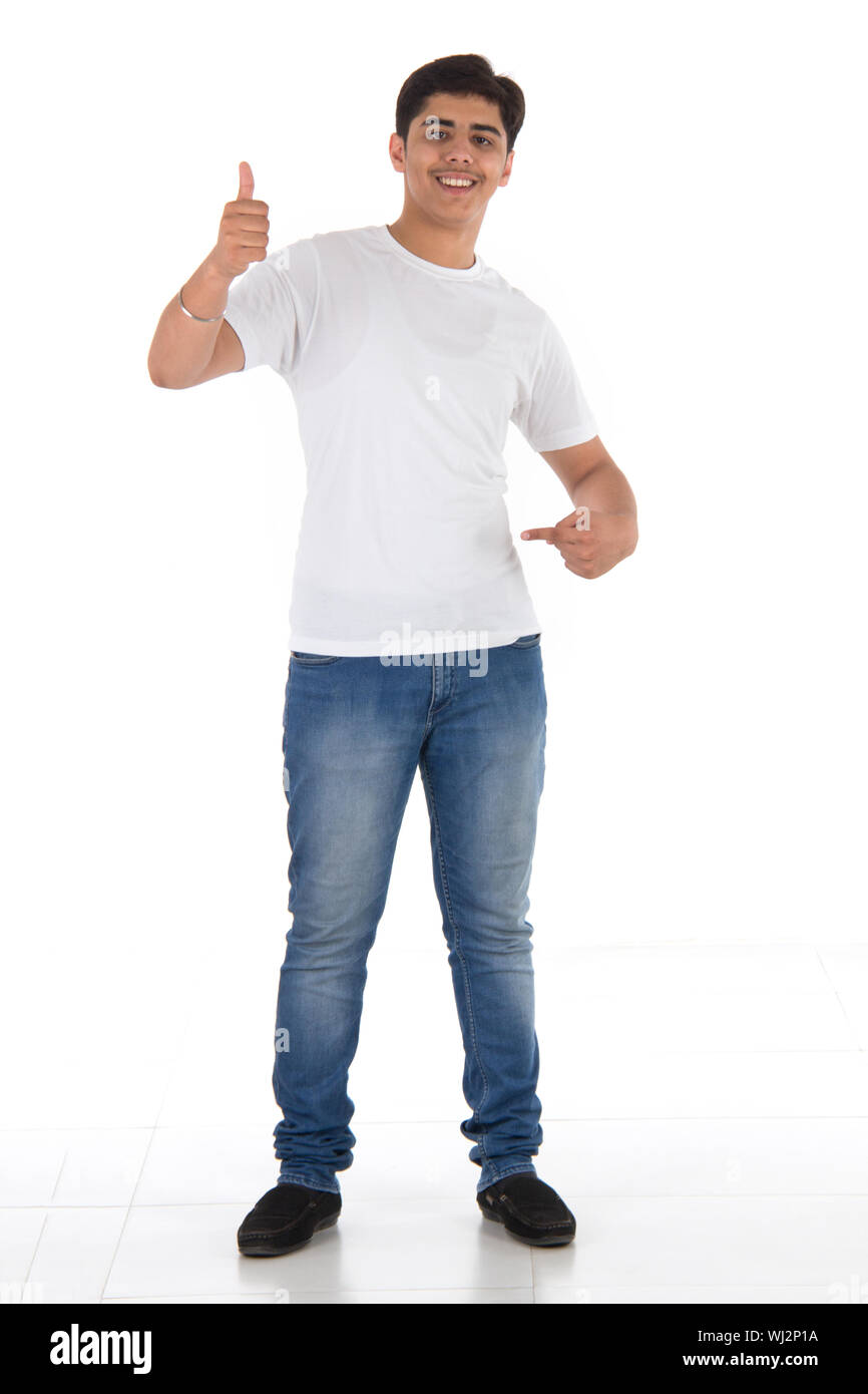 Young man standing and showing thumbs up sign Stock Photo - Alamy