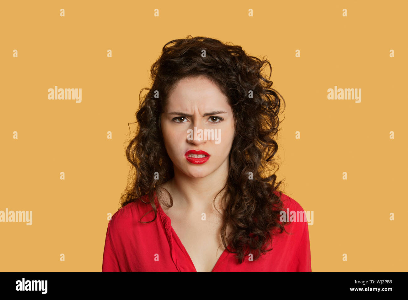 Portrait of angry young woman frowning over colored background Stock ...
