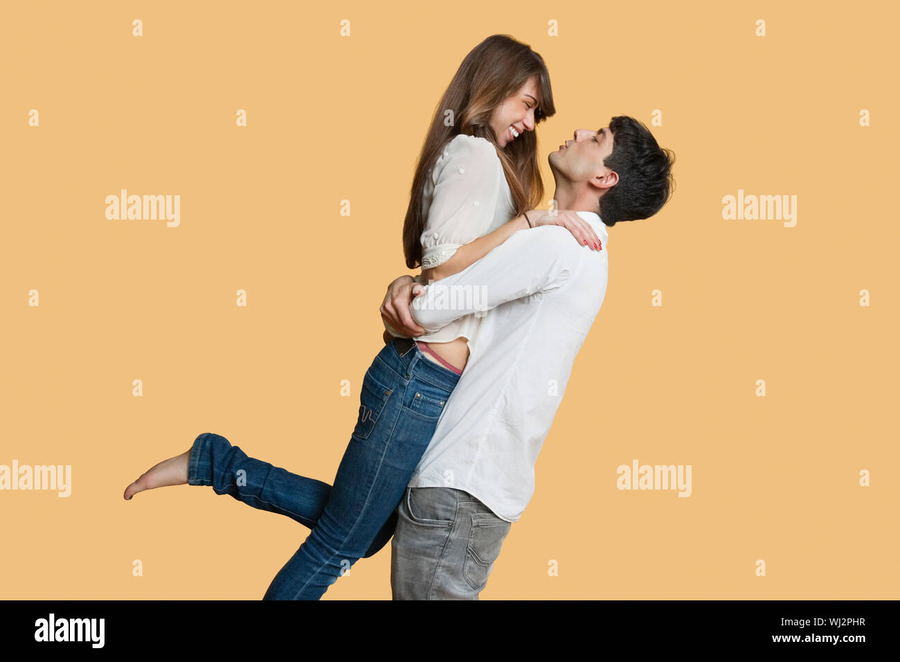 Side view of young couple looking at each other while man carrying ...