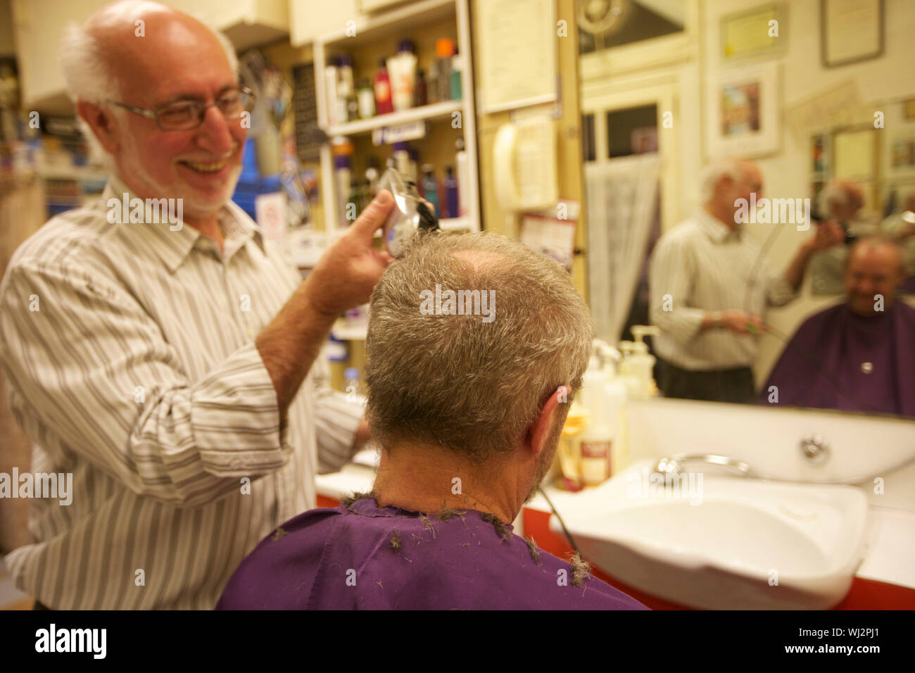 Happy man cutting senior customer's hair with razor Stock Photo - Alamy