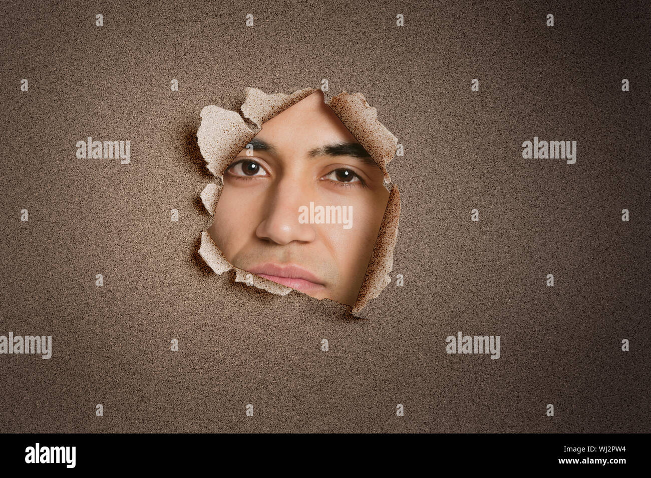 Portrait of a young Indian man peeking from ripped paper hole Stock ...