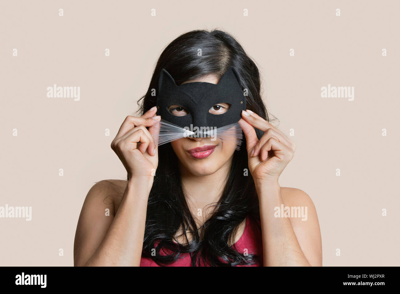 Portrait of a young woman wearing eye mask over colored background ...