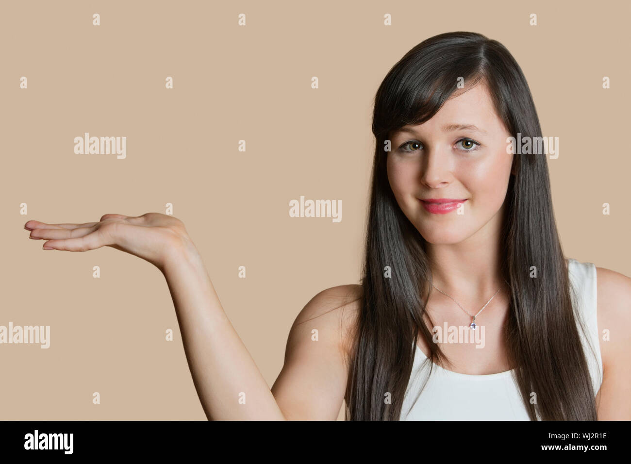 Portrait of a beautiful young woman with empty hand over colored ...