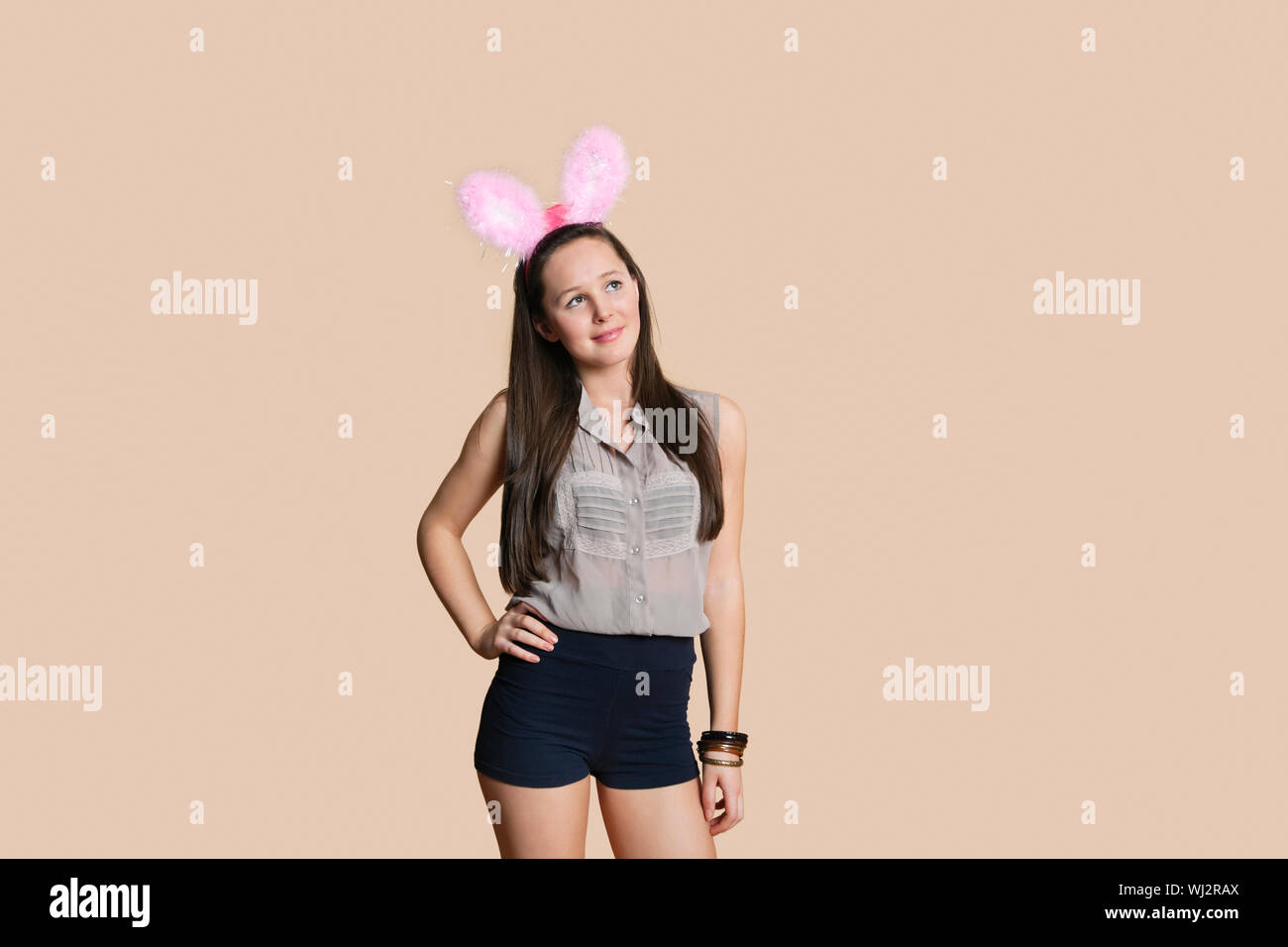 Beautiful young woman wearing rabbit ears while looking away over ...