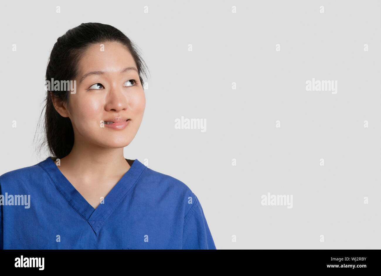Young Asian female doctor looking up over gray background Stock Photo ...