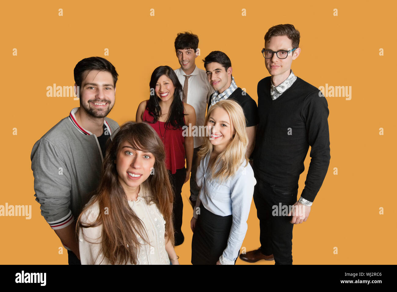 Portrait of group of friends standing together over colored background ...