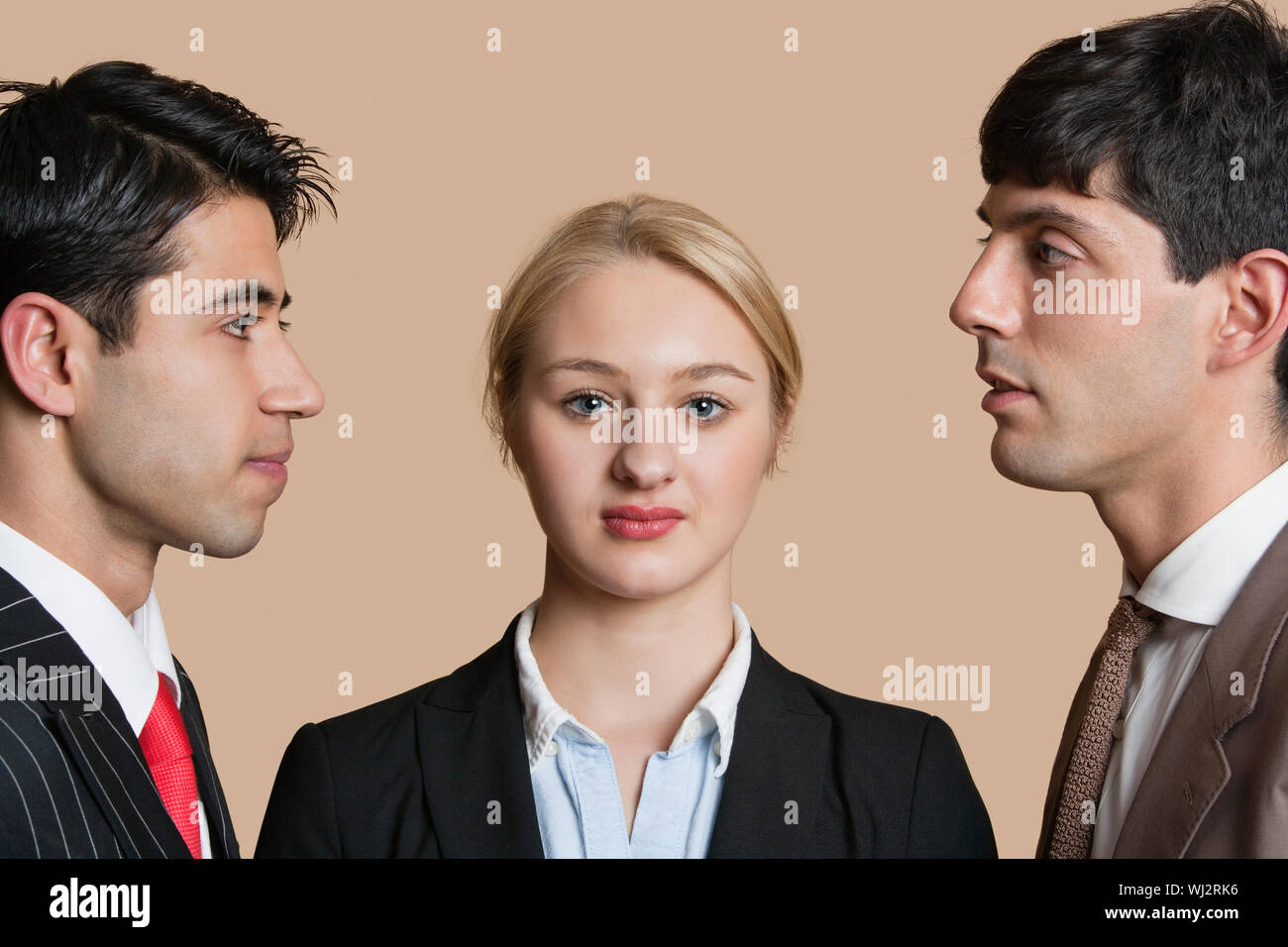 Portrait of a young businesswoman with male colleagues staring at each ...