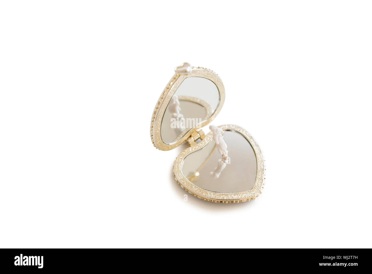 A small figurine standing on an open heart shape pendant over white ...
