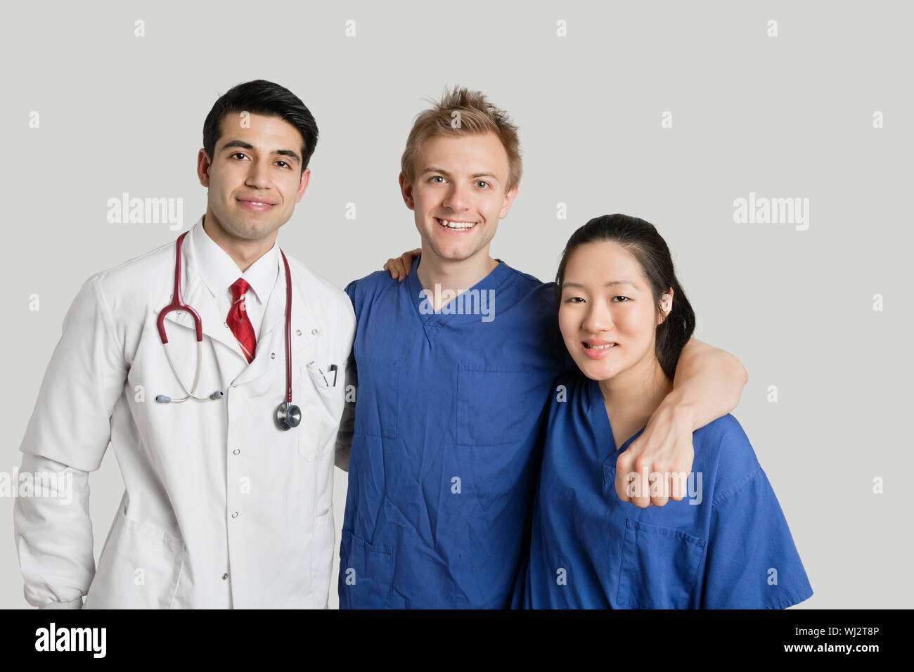 Portrait of friendly medical team standing over gray background Stock ...