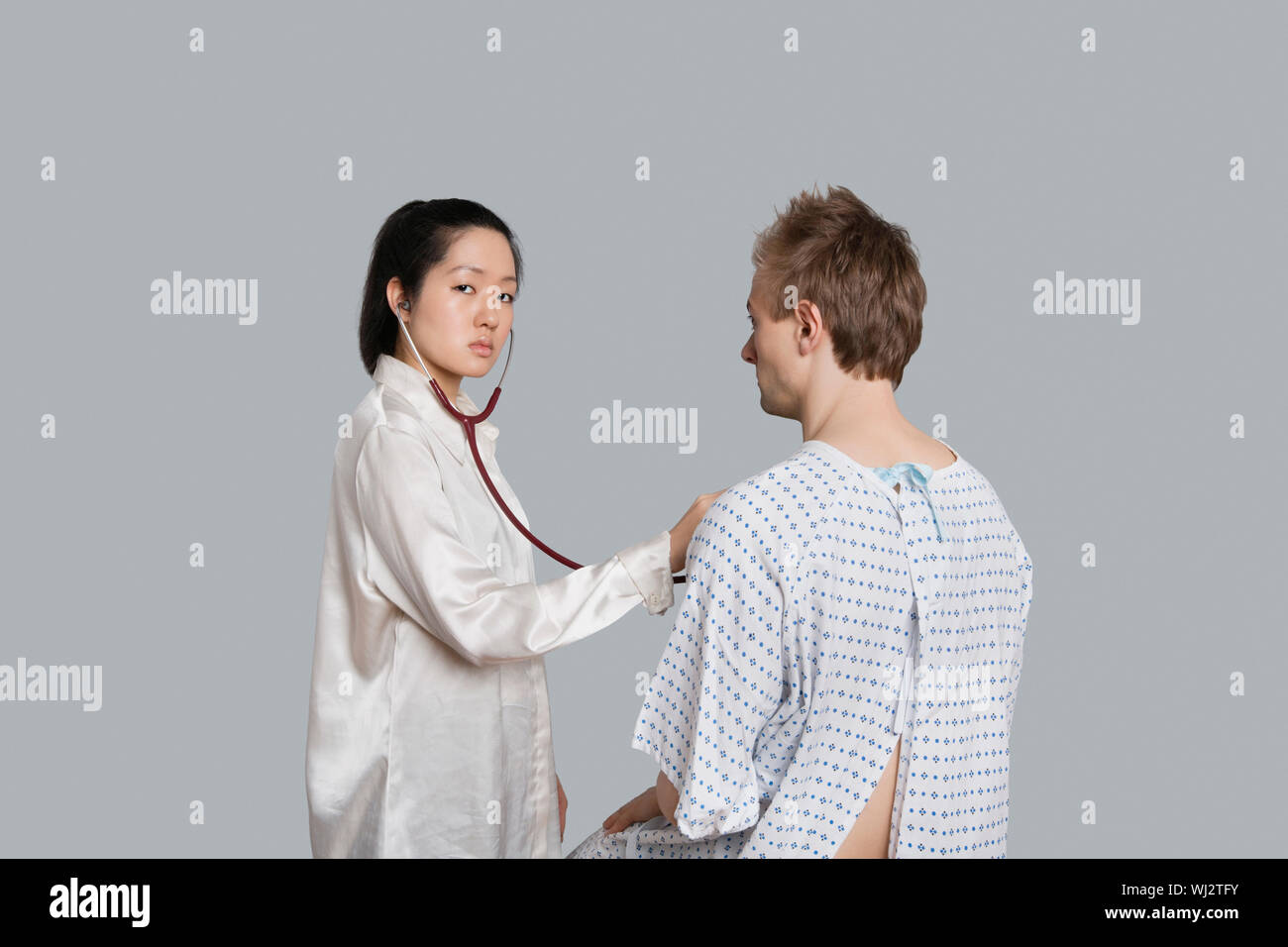 Portrait of a young female doctor examining male patient Stock Photo ...