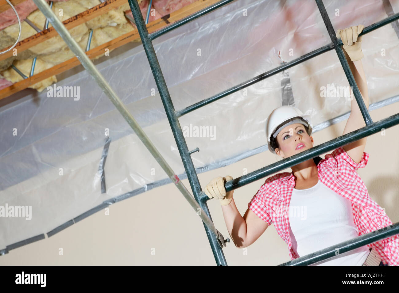 Young female construction worker climbing on scaffold Stock Photo - Alamy