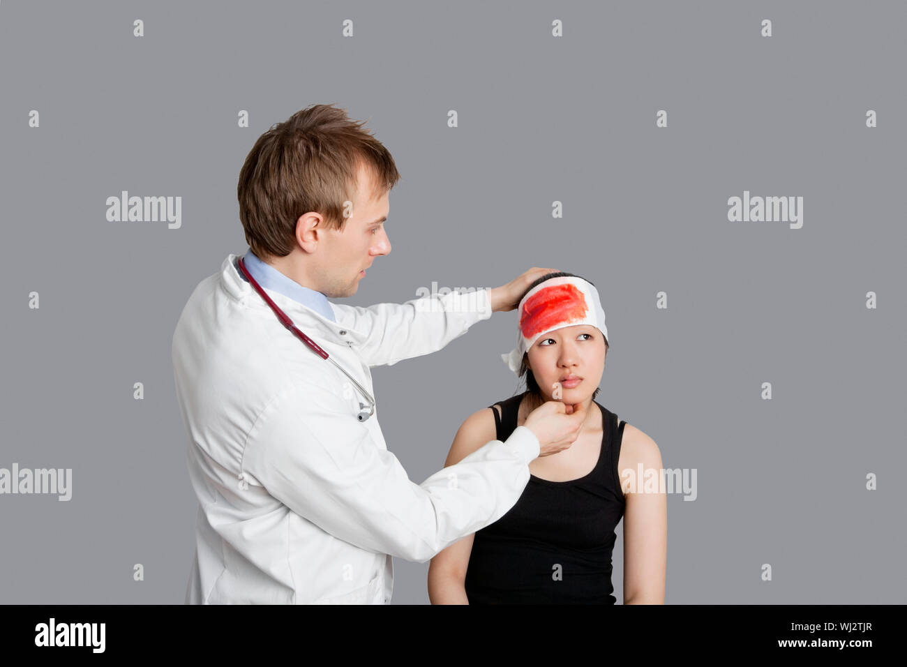 Male doctor treating female patient over colored background Stock Photo ...