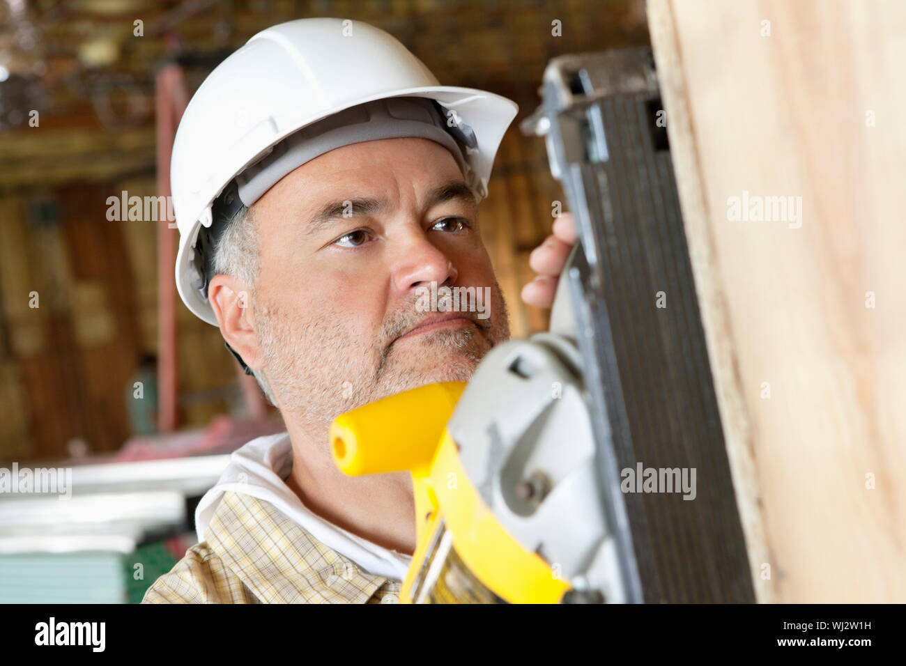 Serious male construction worker cutting wood with a power saw Stock ...