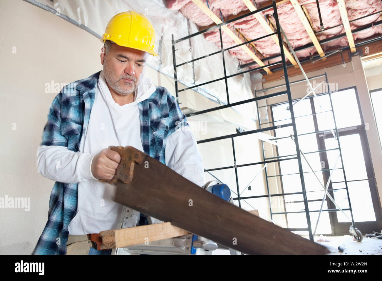 Serious male construction worker cutting wood with handsaw Stock Photo ...