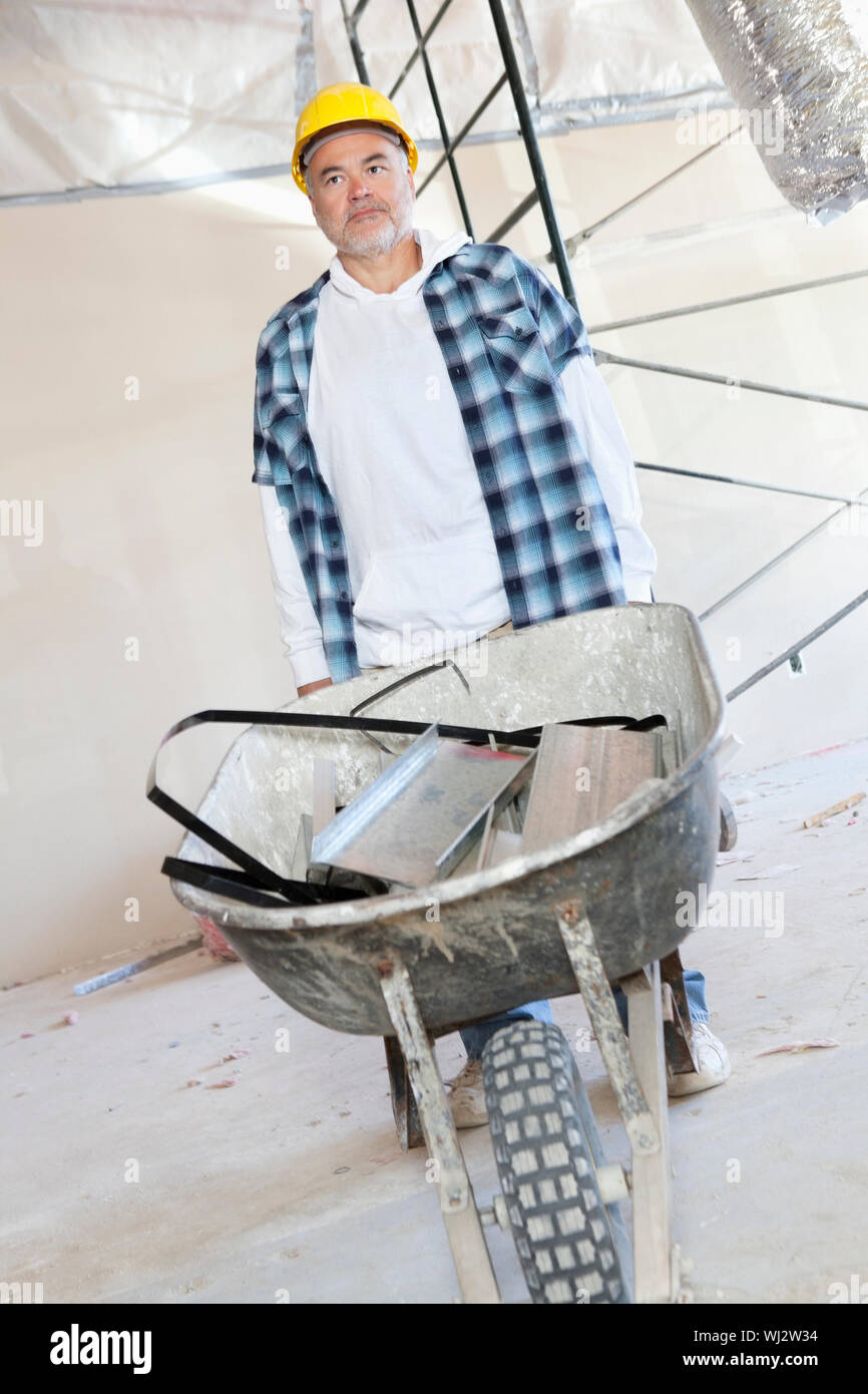 Male construction worker standing with a wheelbarrow Stock Photo - Alamy