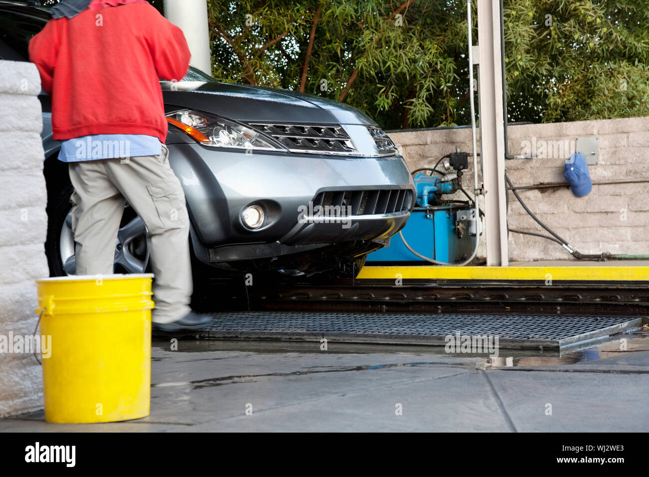 Car wash employee with vehicle on conveyor belt Stock Photo - Alamy
