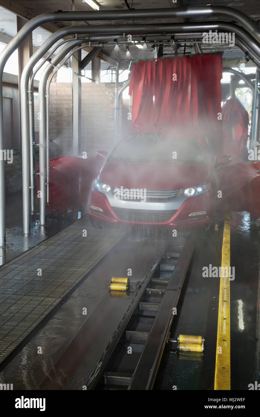 Vehicle on conveyor belt moving through car wash process Stock Photo ...