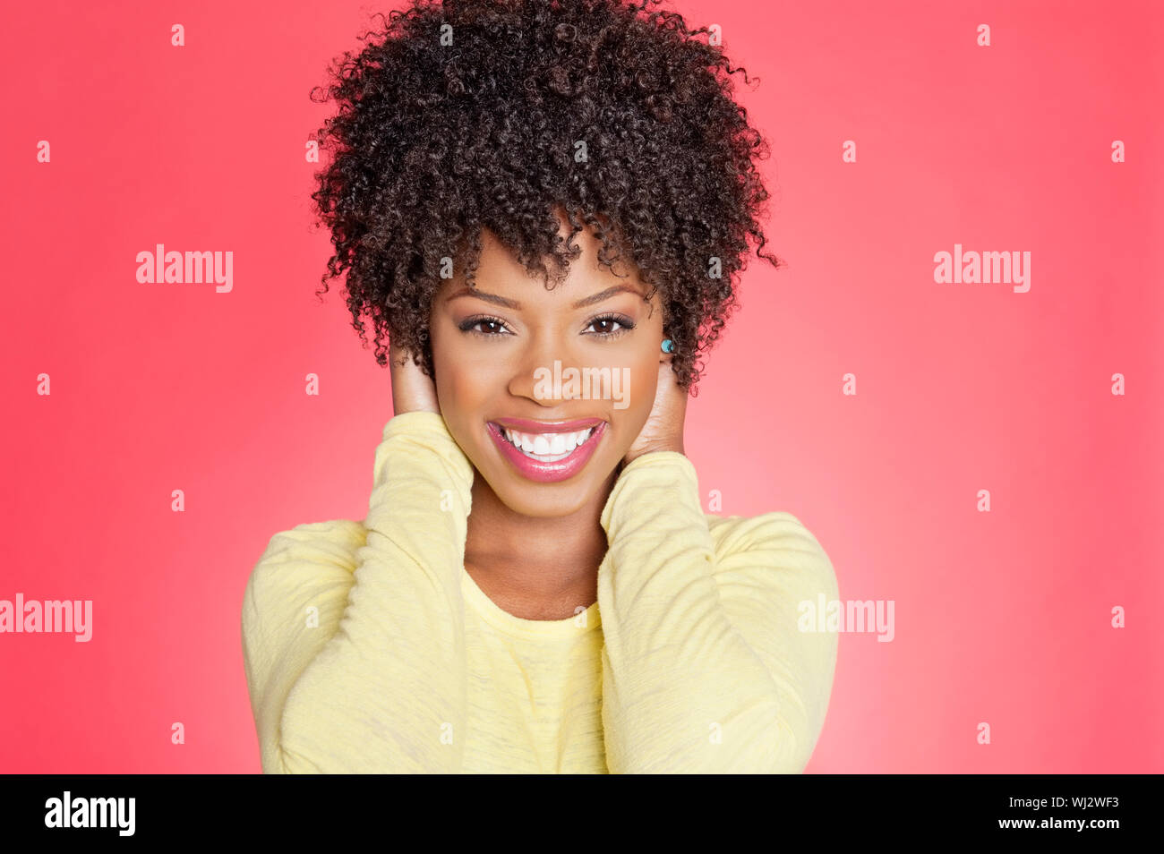 Portrait of a cheerful African American woman with hands over ears ...