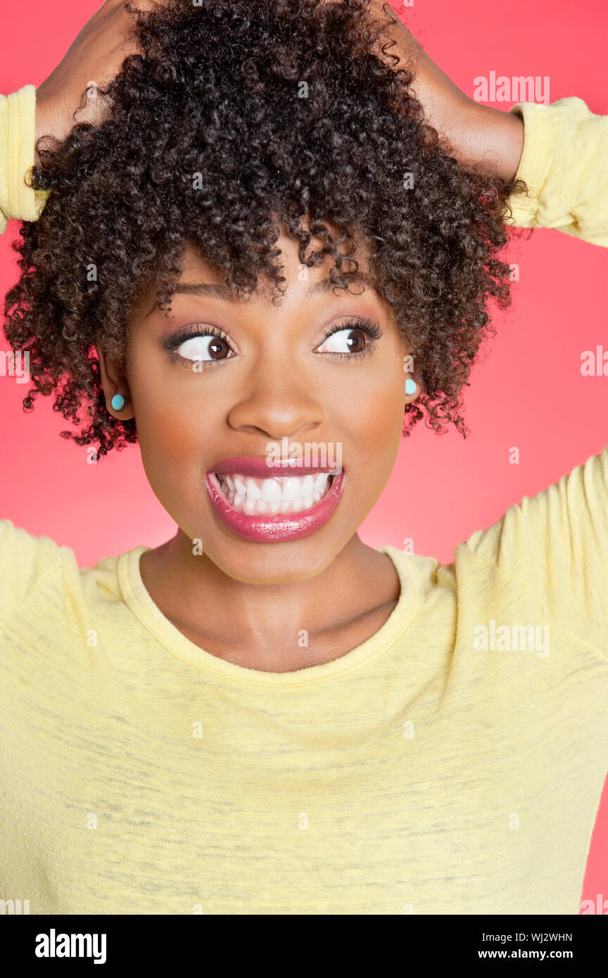 African American looking sideways with hands in hair over colored ...