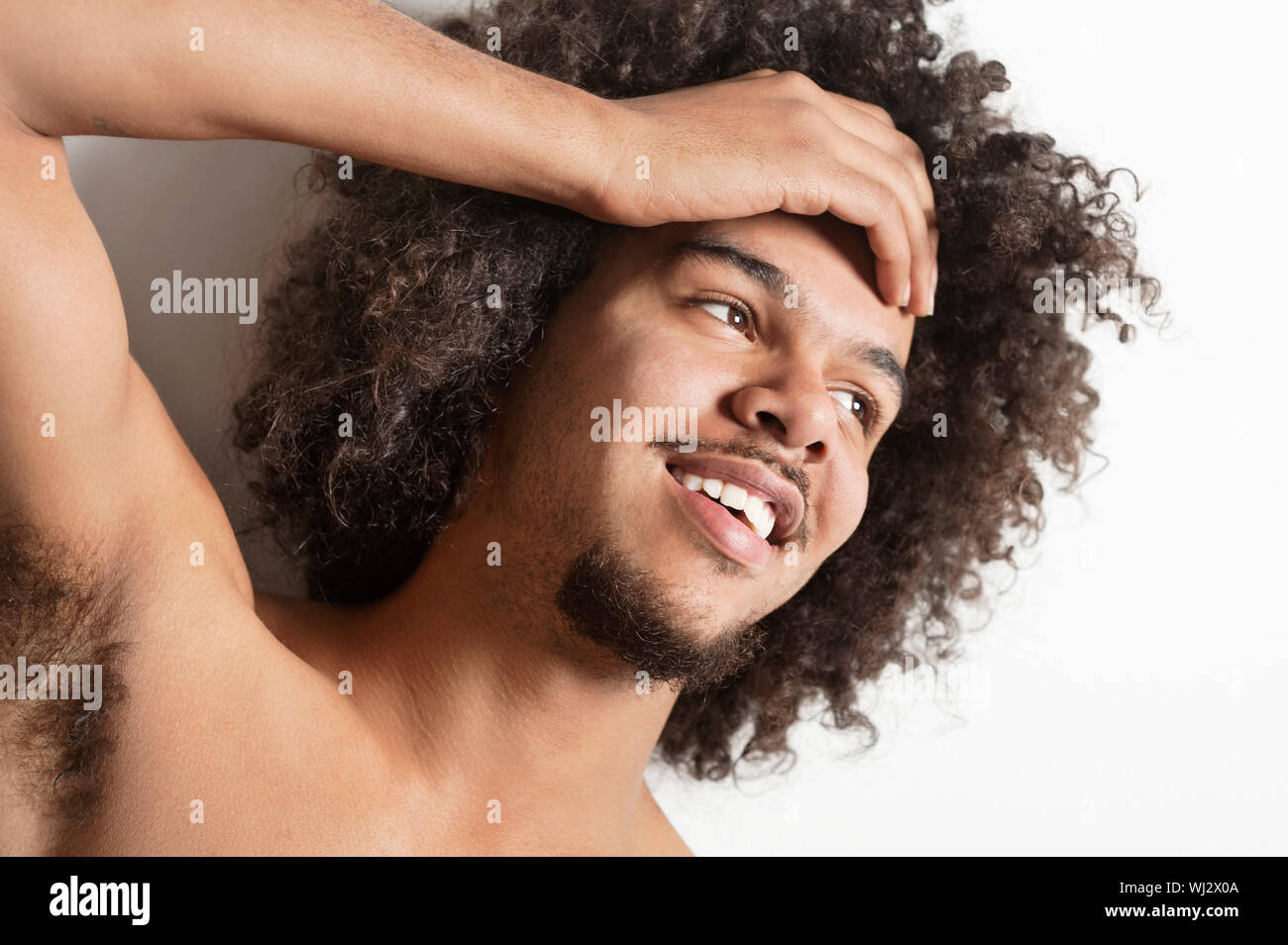 Close-up of a happy young man with hand on head over white background ...