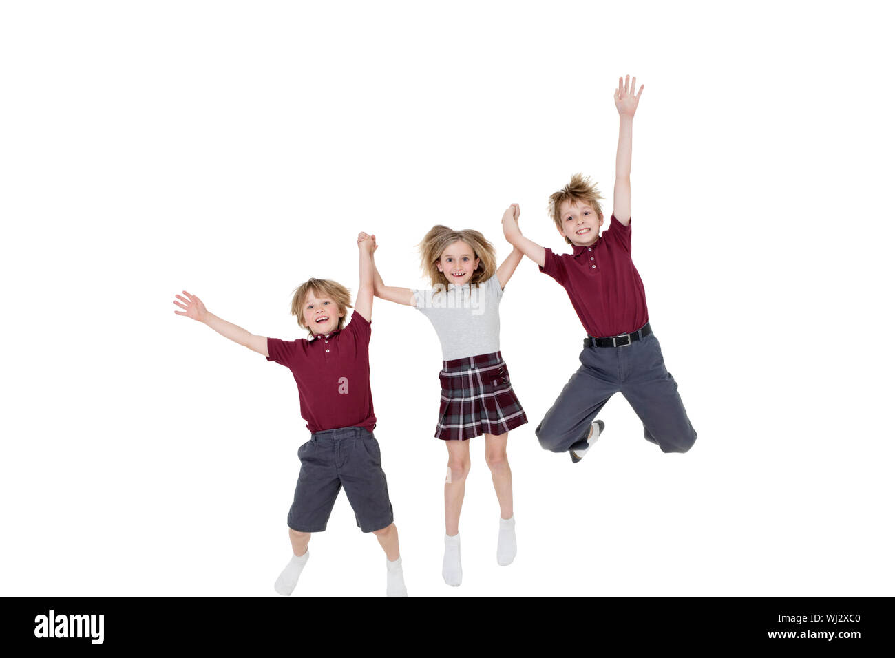 Portrait of happy school children holding hands while jumping over ...