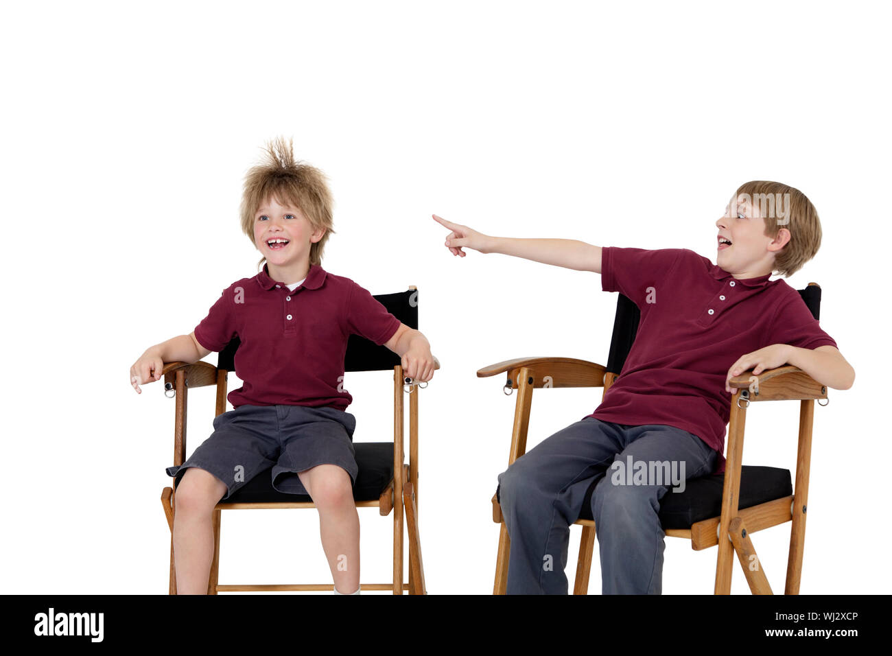 Pre-teen boy pointing at friend's hair while sitting on director's ...