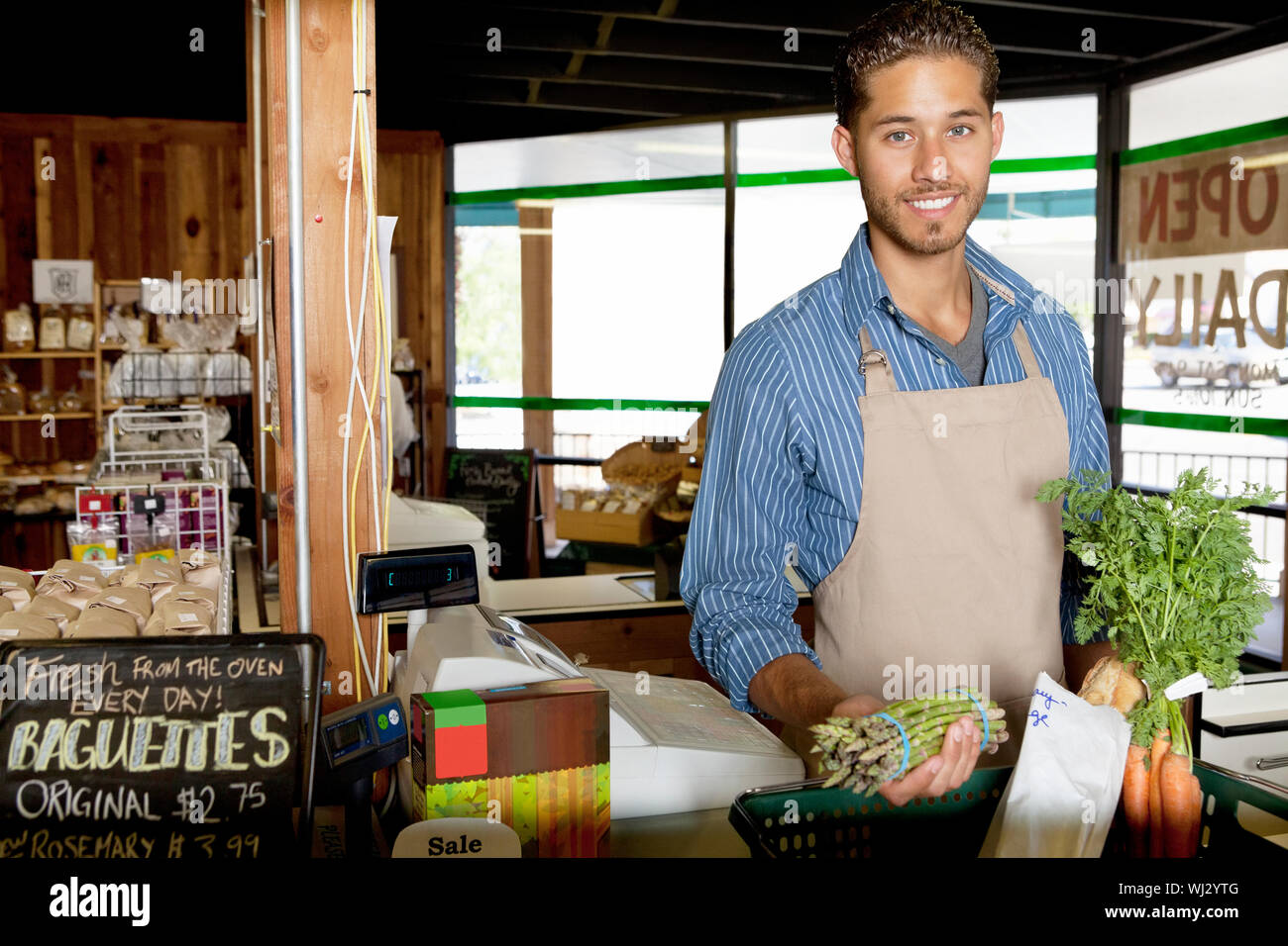 Portrait of handsome young store clerk holding vegetable in supermarket ...