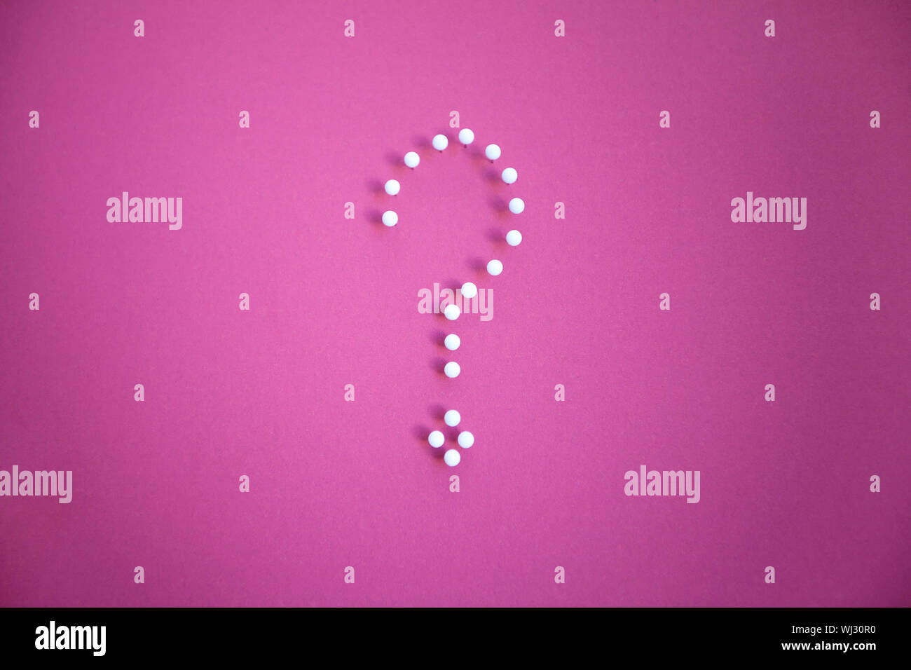 Close-up of push pins forming question mark over pink background Stock ...