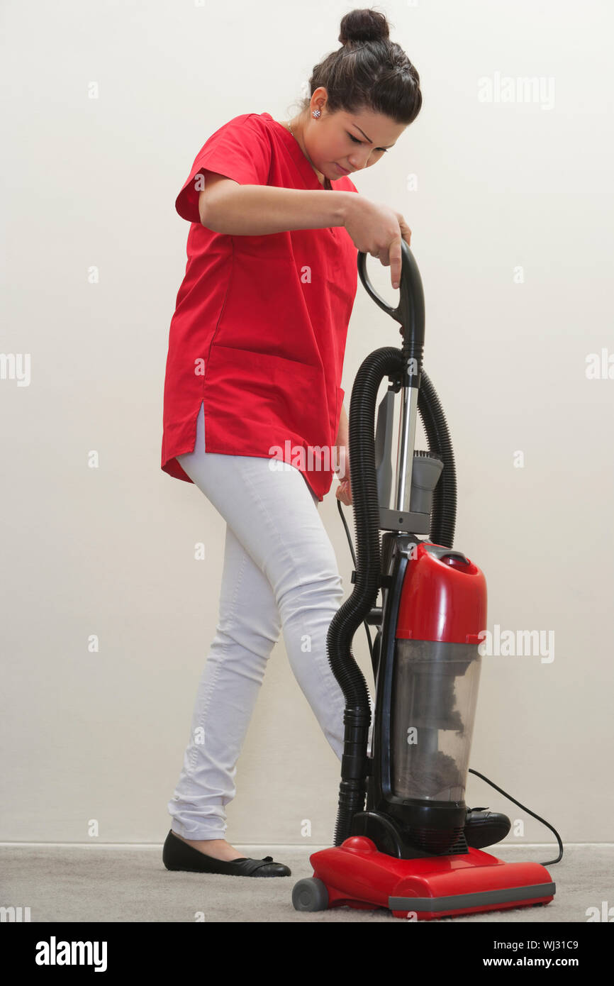 Full length of female housekeeper using vacuum cleaner Stock Photo - Alamy