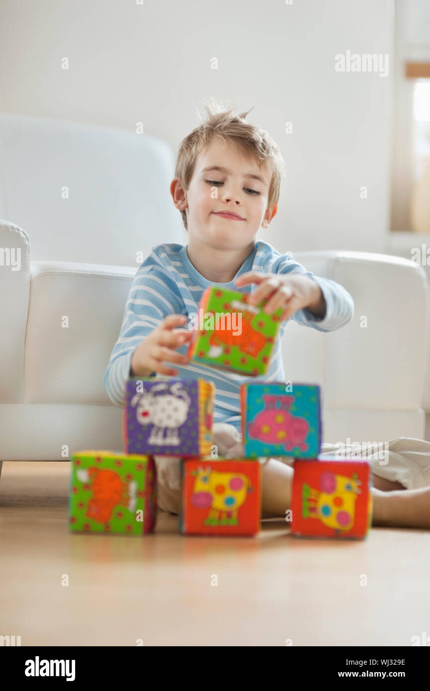 Little boy stacking blocks while sitting on floor Stock Photo - Alamy