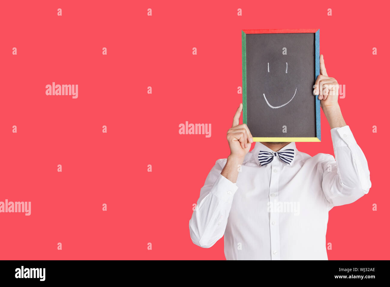 Man holding smiley face sign over red background Stock Photo - Alamy