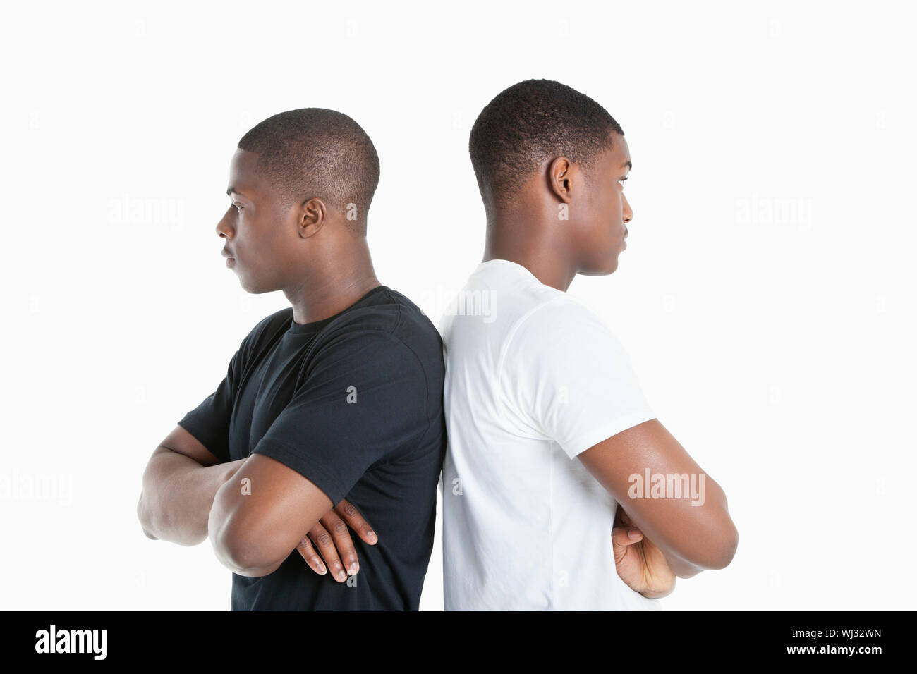 Two male friends standing back to back over gray background Stock Photo ...