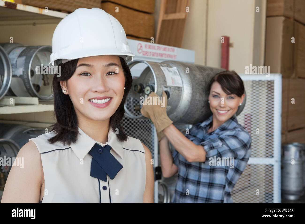 Portrait of woman smiling with female industrial worker carrying ...