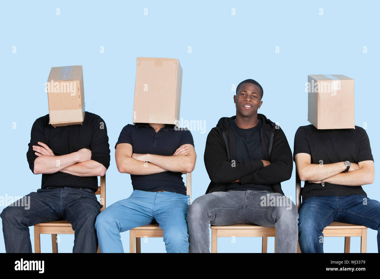 Man with friends faces covered with cardboard boxes as they sit on ...