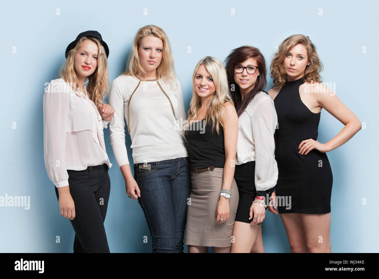 Portrait of five young female friends standing together against light ...