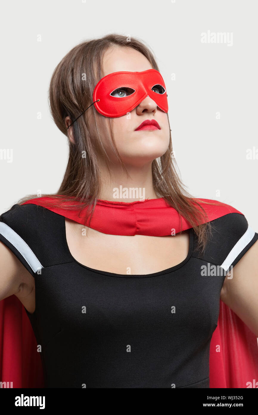 Young woman in superhero costume looking up over gray background Stock ...