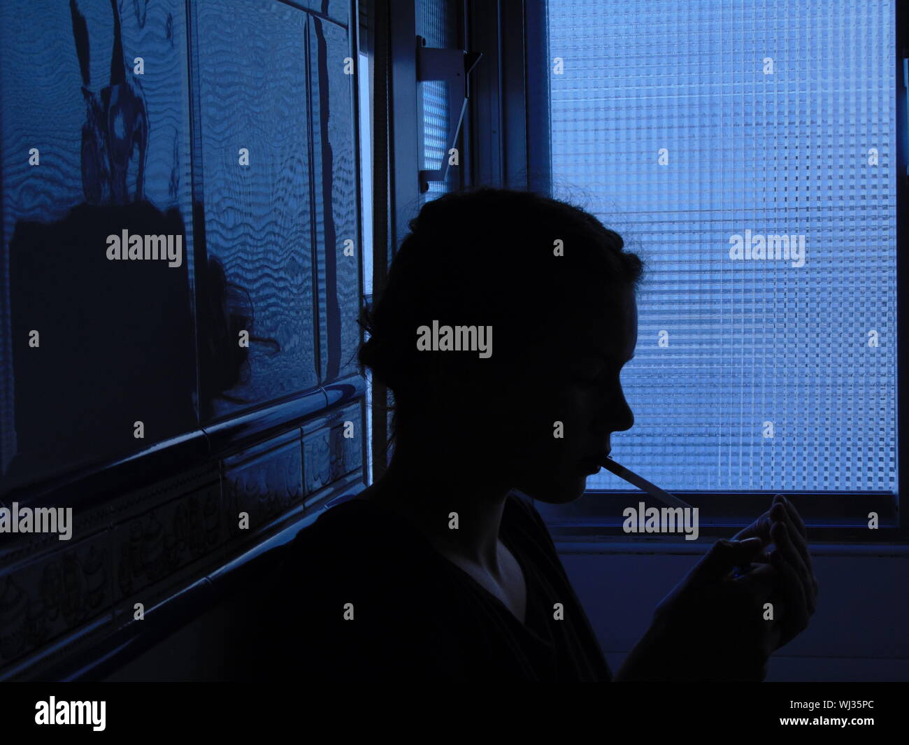 Woman smoking by window hi-res stock photography and images - Alamy